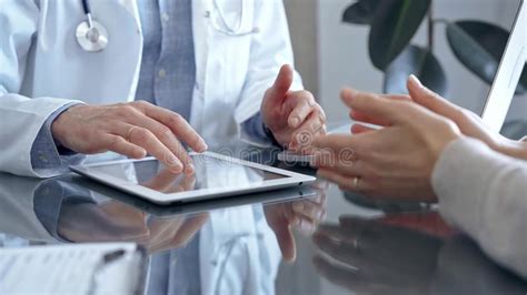 Doctor And Patient Conversation With Tablet Computer In Clinic Office