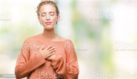아름 다운 젊은 금발의 여자와 웃 고 고립 된 배경 위에 닫힌된 눈과 얼굴에 감사 제스처와 함께 가슴에 손 건강 개념입니다 손에