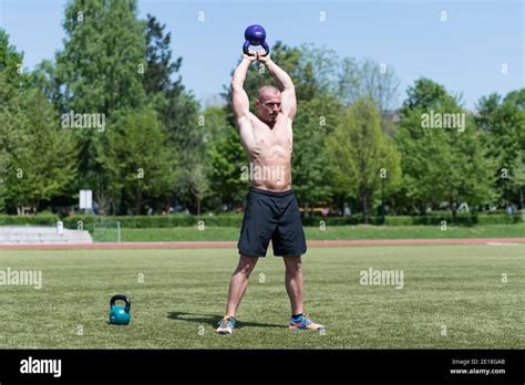 Man Exercising With Kettle Bell Outdoor And Flexing Muscles Muscular Athletic Bodybuilder