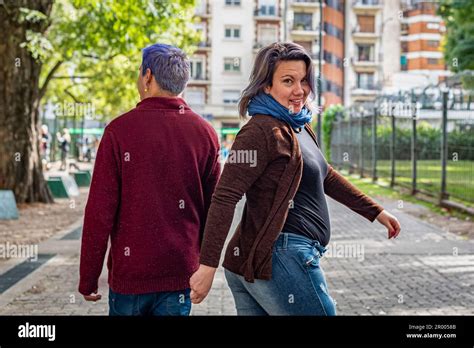 Back View Of Two Friends Walking In The Park She Turns Around To Look
