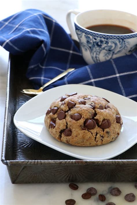 A Chocolate Chip Cookie On A Plate Next To A Cup Of Coffee