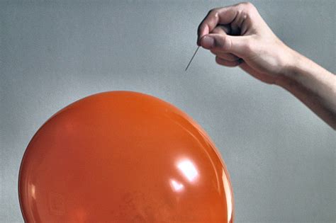 Tangan Lakilaki Memegang Pin Jahit Panjang Di Atas Balon Oranye Yang