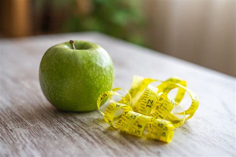 건강한 식습관 균형 잡힌 식단 및 체중 관리를 위한 피트니스 목표를 나타내는 측정 테이프가 있는 녹색 사과 0명에 대한 스톡
