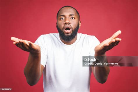 바보 같은 젊은 아프리카 남자의 클로즈업 초상화 왜 그렇게 걱정 하는 문제 나도 몰라 왜 물어 밖으로 팔 빨간색 배경에 격리되었습니다 부정적인 인간의 감정 얼굴 표정 감정