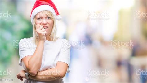 젊은 아름 다운 금발 여자 찾고 강조 하 고 손톱을 물어 뜯고 입에 손으로 긴장 고립 된 배경 위에 크리스마스 모자를 쓰고 불안 문제입니다 감정에 대한 스톡 사진 및 기타
