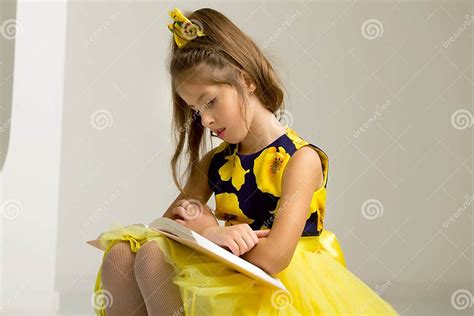 Школьница девочки сидит на лестнице и читает книгу Стоковое Изображение изображение