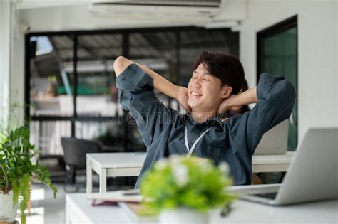 A Happy Asian Businessman Is Leaning Back In His Chair Feeling