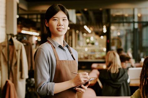 Smiling Asian Waitress Holding Notepad In Busy Cafe Stock Image Image