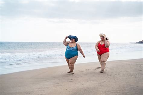 여름 방학 동안 재미를 해변에서 걷는 플러스 크기 여성 매력적인 여성은 함께 웃음 과체중 몸과 여행 개념 2명에 대한 스톡 사진