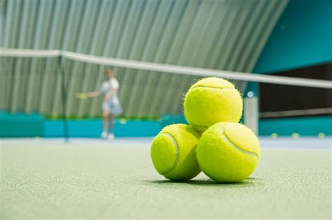 스포티한 라이프스타일의 개념 테니스 홀에서 테니스를 치는 소녀의 배경에 대해 바닥에 있는 테니스 공 개념에 대한 스톡 사진 및