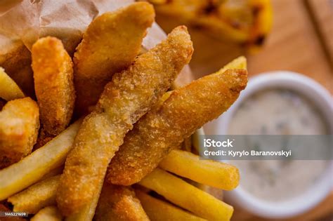 접시에 감자 튀김과 함께 반죽에 튀긴 대구 흰색 세라믹 냄비에 마늘 소스와 함께 나무 보드에 양피지와 함께 나무 배경입니다 0명에 대한 스톡 사진 및 기타 이미지 Istock