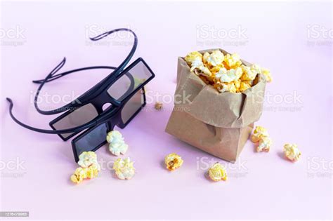 분홍색 표면에 팝콘이 있는 종이 컵 인근에는 3d 안경과 Tv 리모컨이 있습니다 검역으로 영화를 보고 3차원 형태에 대한 스톡