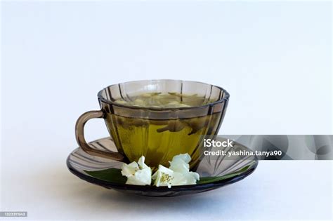차 한 잔 하얀 배경에 고립 된 재스민의 꽃이있는 허브 핫 재스민 차가있는 다크 글래스 컵 테이블에 녹색 잎검은 머그잔에 건강한 음료 복사 공간을 복사합니다 0명에 대한
