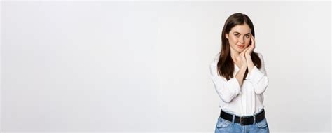 아름 다운 젊은 갈색 머리 여자는 부드럽게 그녀의 얼굴 피부를 만지고 미소 요염한 부드러운 포즈를 다시 무료 사진