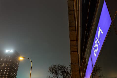 마드리드의 파세오 데 라 카스텔라나에 위치한 은행 지점에 Bbva 은행 로고가 있는 발광 패널 배경에는 겨울 밤의 안개 속에서