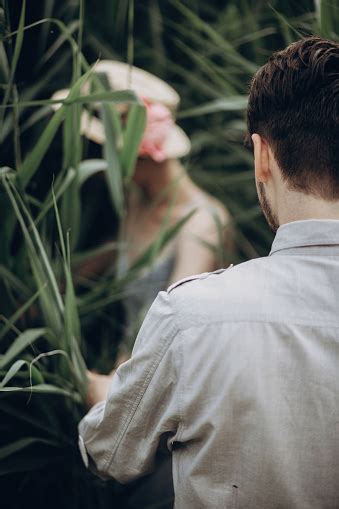 Hipster 커플 여름 공원에 호수에서 지팡이에 산책 세련 된 현대 드레스와 모란 편안한 강 및 높은 리드와 밀 짚 모자 남녀 행복 한 소박한 결혼식 강에 대한 스톡 사진