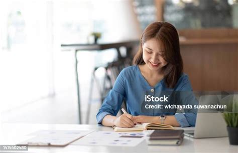 사무실 테이블에 앉아있는 동안 노트북 컴퓨터에서 일하는 예쁜 소녀를 웃고 일기에 메모를합니다 계산기에 대한 스톡 사진 및 기타 이미지 Istock