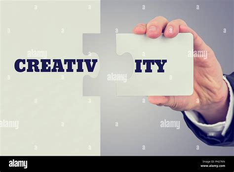 Conceptual Image Of Creativity With The Word Split Over Two Matching Puzzle Pieces Held In The