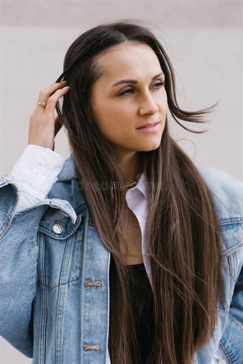 Young Caucasian Woman With Long Brown Hair Is Wearing A Blue Jacket And