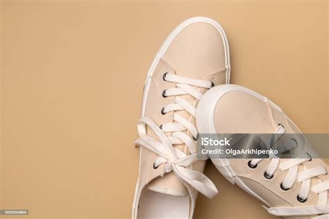 갈색 배경에 베이지색 패브릭 스니커즈가 평면적으로 놓여 있다 패션 스니커즈 끈이 달린 캐주얼 운동화 세련된 여름 봄 스니커즈