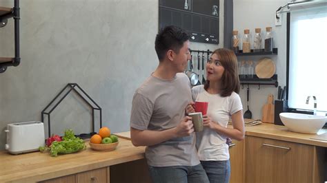 Beautiful Happy Asian Couple Are Drinking A Cup Of Coffee Together In