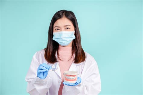 아시아 치과 의사는 파란색 배경 고립 된 스튜디오 샷에 올바른 치열 교정 치료 후를 포함하여 구강 및 치과 치료를 돌보는 방법을