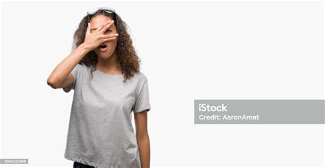 아름 다운 젊은 히스패닉 여자 얼굴과 손으로 눈을 덮고 충격 엿보기 안경을 쓰고 당황된 하는 표정으로 손가락을 통해 찾고 T