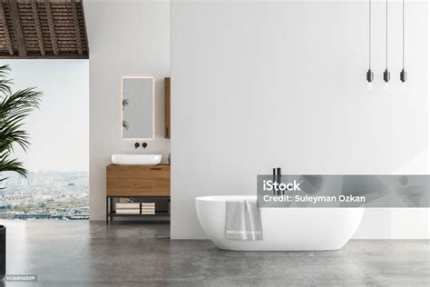 콘크리트 바닥 도시 전망의 창문 흰 벽 큰 욕조 수직 거울과 나무 화장대가 있는 흰색 세면대가 있는 세련된 욕실 인테리어 3d