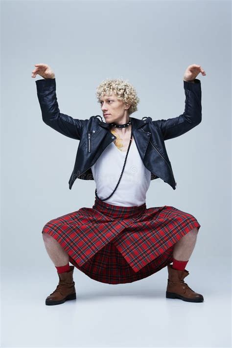 Man In Kilt And Leather Jacket Posing With Raised Arms Embodying Mix