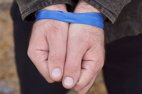 The Hands Of A Male Criminal Are Tied And Wrapped With Blue Tape Stock