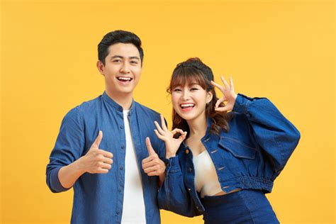 흥분 아름 다운 아시아 커플 엄지 손가락 제스처 뭔가 하 고 오렌지 벽에 대 한 협력 에 동의 표시 좋은 일을 했다 표시 승인