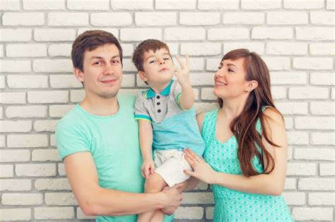Retrato De Familia Joven Feliz Y Sonriente Sobre Fondo De Pared De Ladrillo Padre Y Madre Con