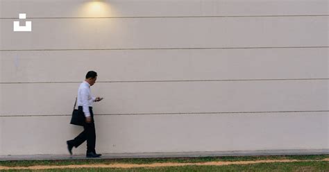 흰 셔츠와 검은 바지를 입은 남자가 회색 콘크리트 바닥에 서 있다 사진 Unsplash의 무료 사무실 이미지