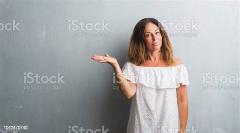 중세 스페인 여자 웃는 쾌활 한 제시 하 고 카메라를 보고 손바닥으로 가리키는 회색 그런 지 벽을 통해 서 가리키기에 대한 스톡 사진 및 기타 이미지 Istock