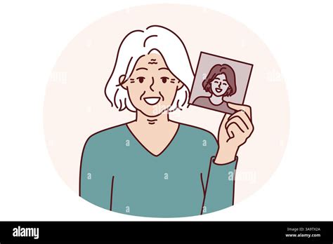 Elderly Gray Haired Woman Shows Own Old Photo For Concept Of Memory Of Past And Nostalgia