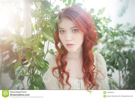 Tender Portrait Of A Young Beautiful Dreamy Redhead Woman Among Foliage