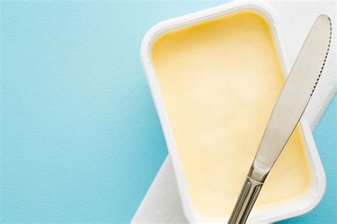 연한 황색 마가린과 나이프의 플라스틱 팩을 열었습니다 근접 촬영 파스텔 블루 데스크에 텍스트나 로고가 있는 빈 공간 평면도