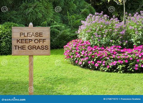 Please Keep Off The Grass Concept With Wooden Pole On A Green Meadow