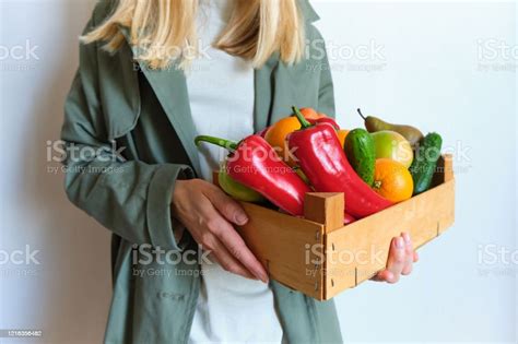 천연 신선한 야채와 과일 나무 상자를 들고 트렌치 코트에 여자 건강한 식생활 바이오 유기농 식품 식료품 점에서 쇼핑 여성