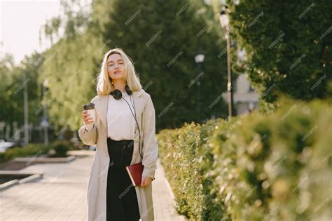 Blonde Se Promène Dans La Ville Dété Avec Une Tasse De Café Photo Gratuite