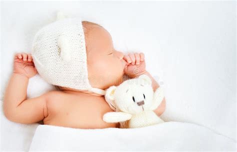 Милый Newborn младенец в шляпе медведя спит с плюшевым медвежонком