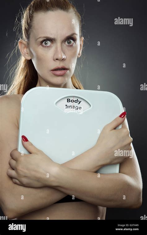 Woman Shot In The Studio Low Key Lighting Holding Weight Scales With The Words Body Image