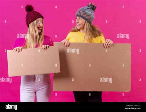 Two Females With Hats And Colorful Blouses Holding Empty Cardboard For