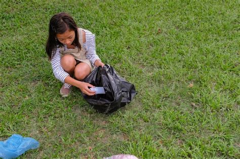 Premium Photo Girl Collecting Garbage On Field