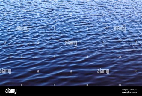Detailed Close Up View On Water Surfaces With Waves And Ripples And The Sunlight Reflecting At