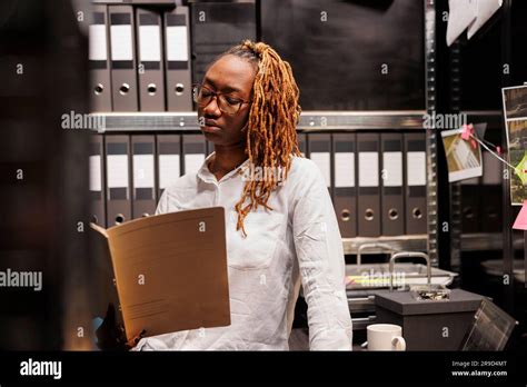 Policewoman Standing Near Crime Case Folders Shelf And Reading Report