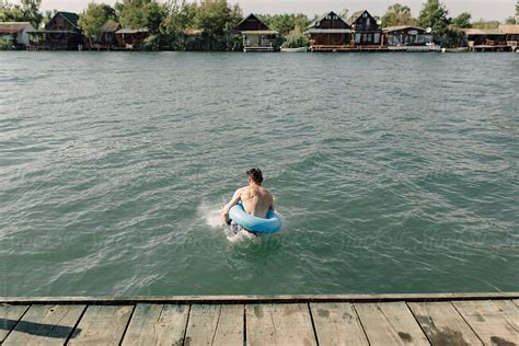 A Back View Image Of A Man Diving Into The Water Wearing A Swim Ring By Stocksy Contributor