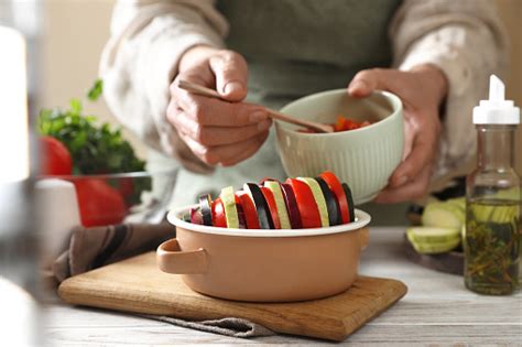 맛있는 라따뚜이 요리 하얀 나무 테이블에서 그릇에 신선한 야채를 입히는 여자 클로즈업 라타투이에 대한 스톡 사진 및 기타 이미지