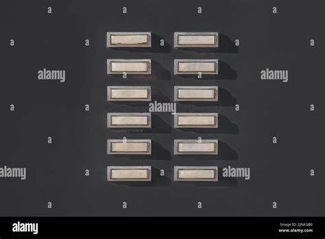 A Closeup Of Empty Name Tags Of Multiple Doorbell Buttons In Black Wall
