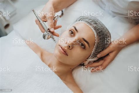 여자는 장치를 가진 얼굴 산소 치료의 절차를 얻는 것에 직면한다 상단 보기 미용학의 스킨 케어 20 24세에 대한 스톡 사진 및